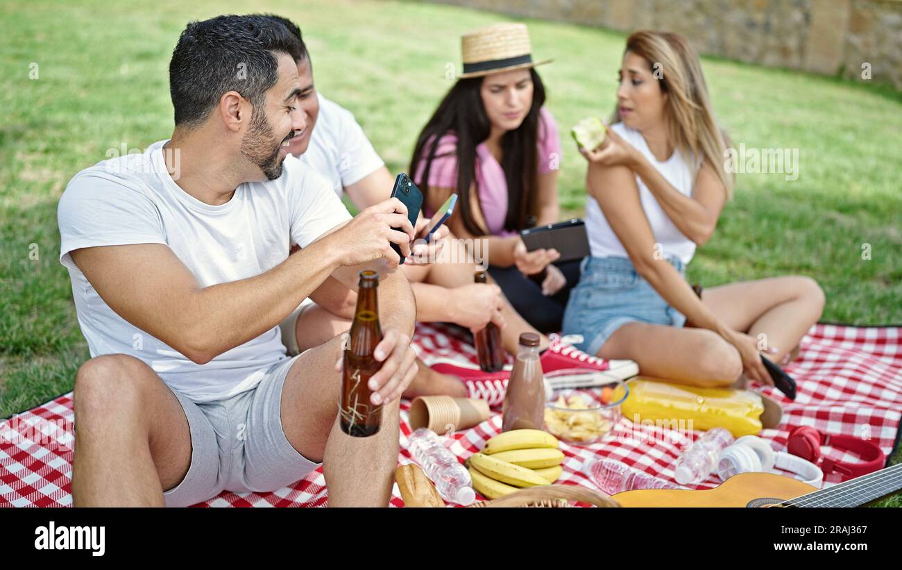 Group of people having picnic using smartphones and touchpad at park Stock Photo - Alamy