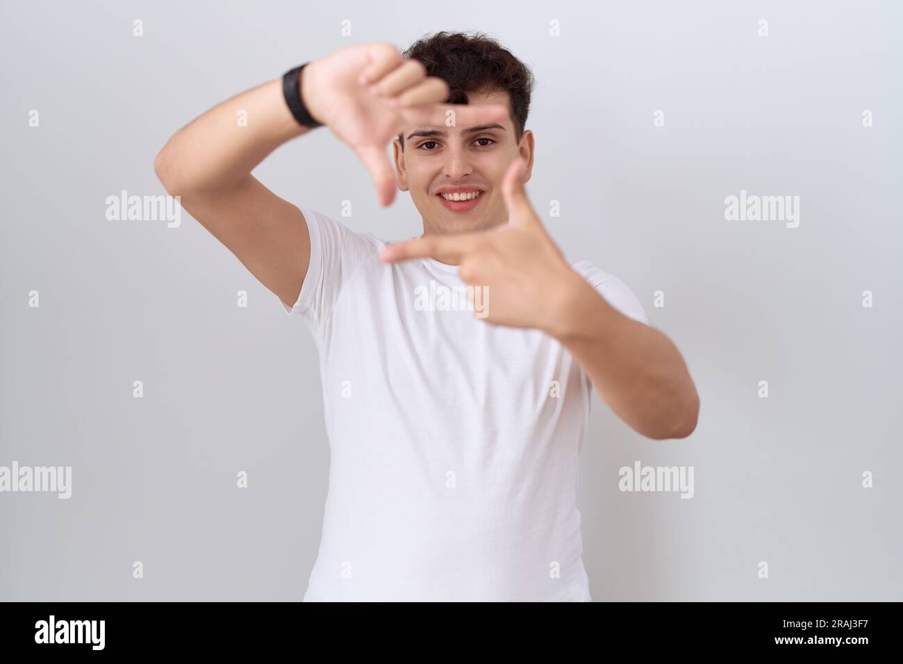 Young non binary man wearing casual white t shirt smiling making frame ...