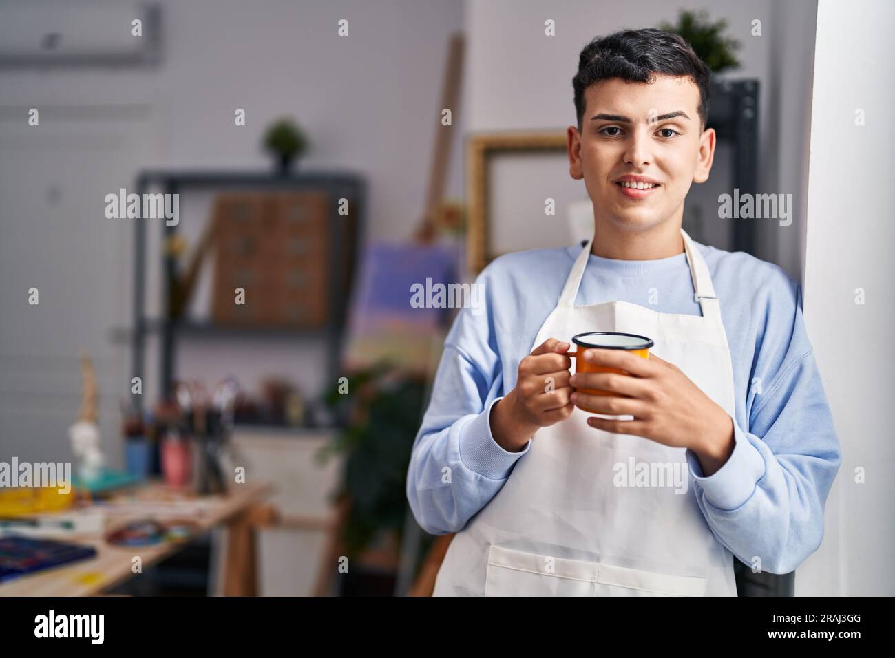 Young non binary man artist smiling confident drinking coffee at art ...