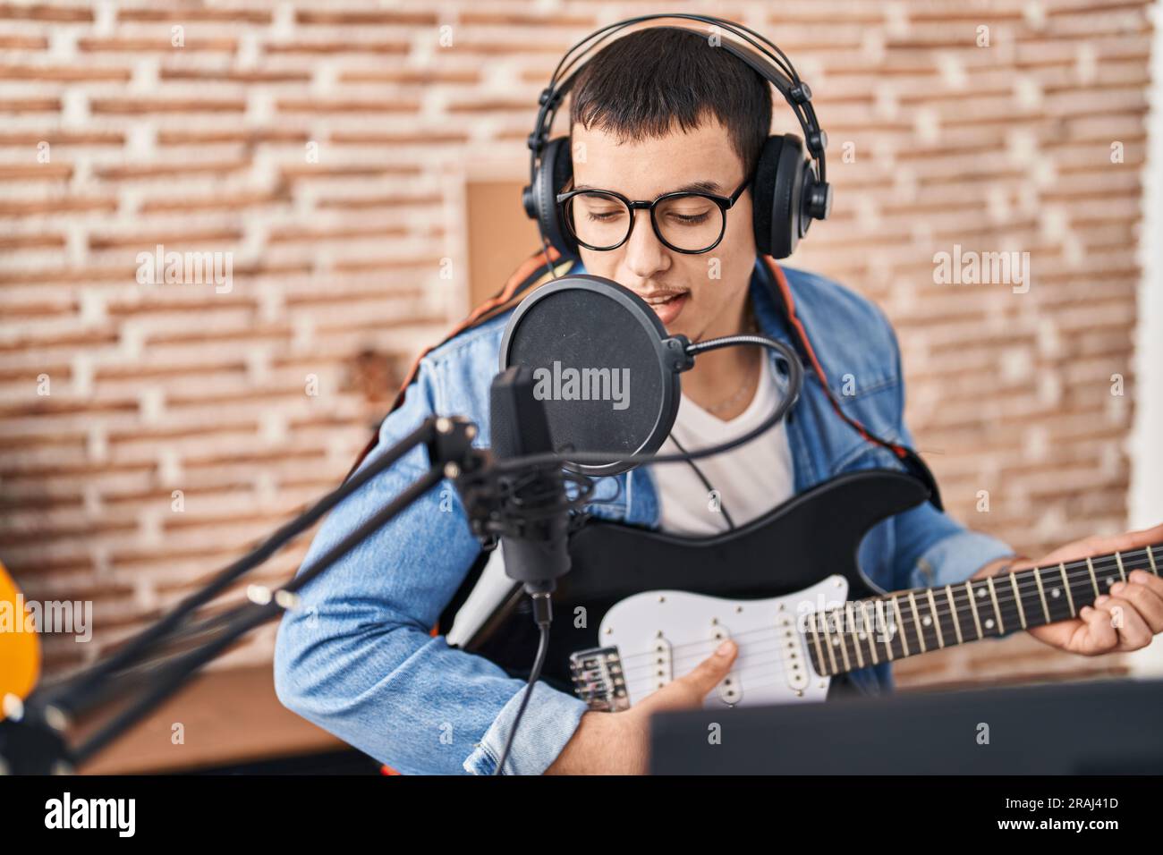 Young man artist singing song playing electrical guitar at music studio ...