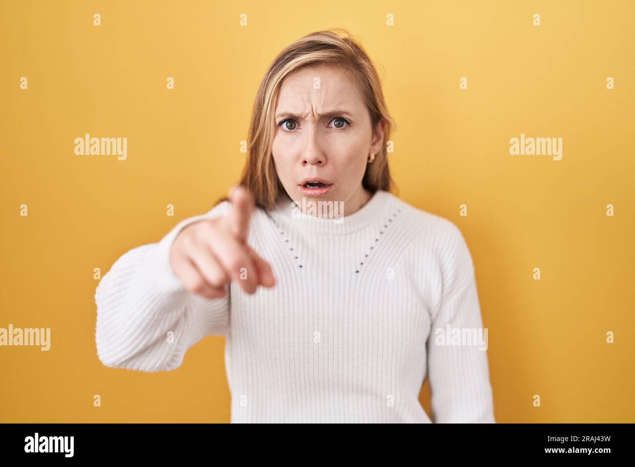 Young caucasian woman wearing white sweater over yellow background ...
