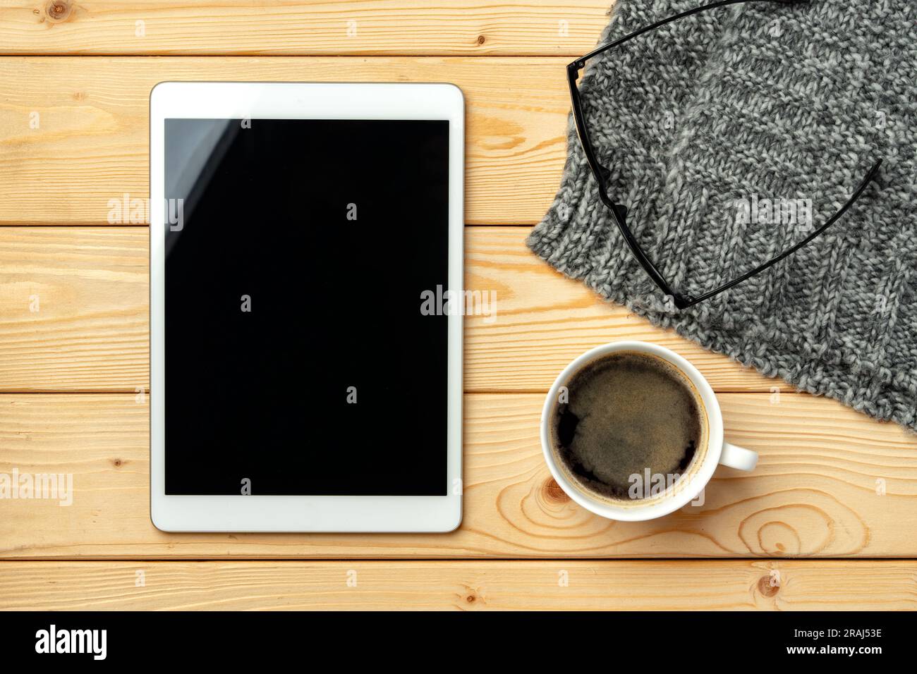 Top view of wooden table with white digital tablet with black screen on ...