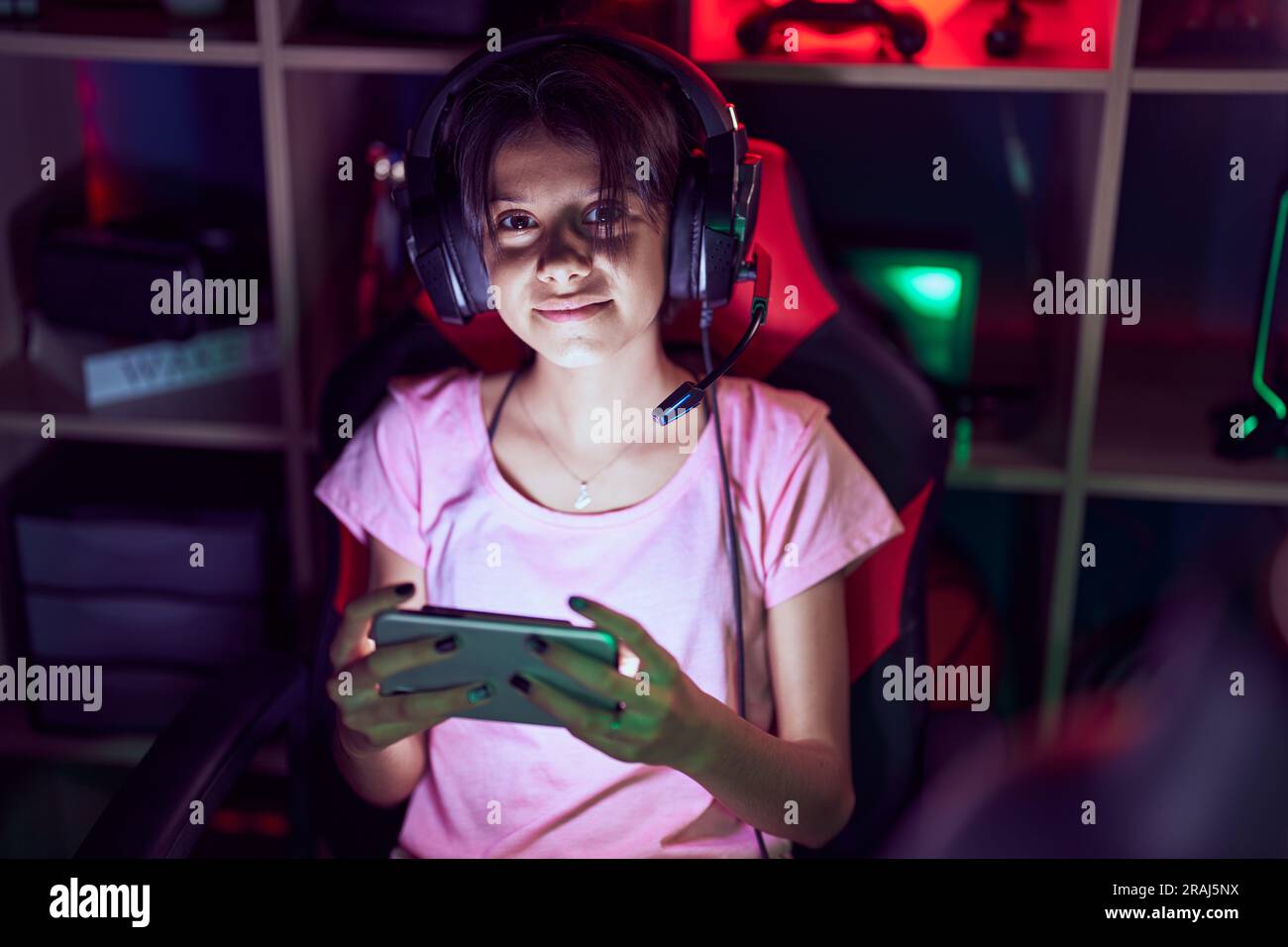 Adorable hispanic girl streamer playing video game using smartphone at ...