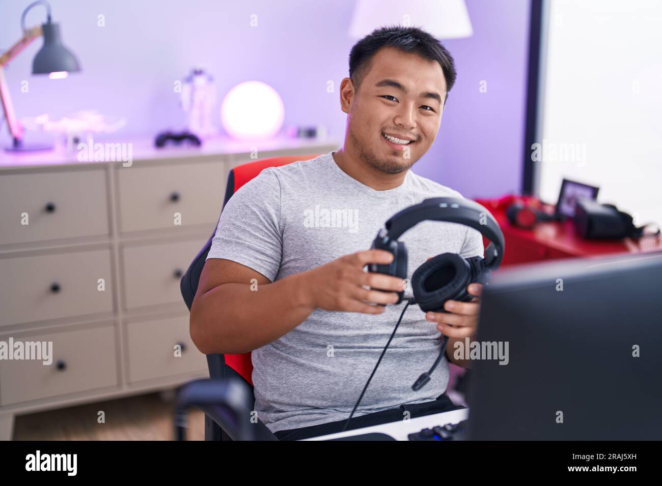 Young chinese man streamer smiling confident holding headphones at ...