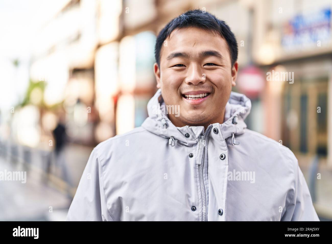 Young chinese man smiling confident standing at street Stock Photo - Alamy