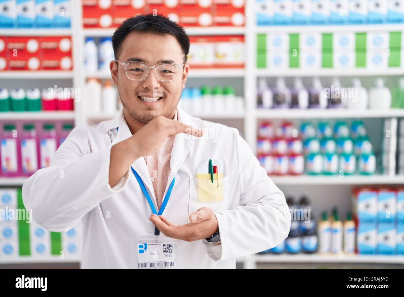 Chinese young man working at pharmacy drugstore gesturing with hands ...