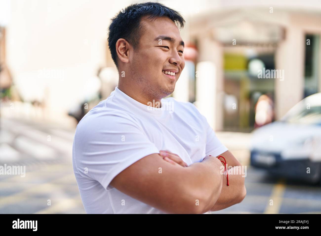 Young chinese man smiling confident standing with arms crossed gesture ...