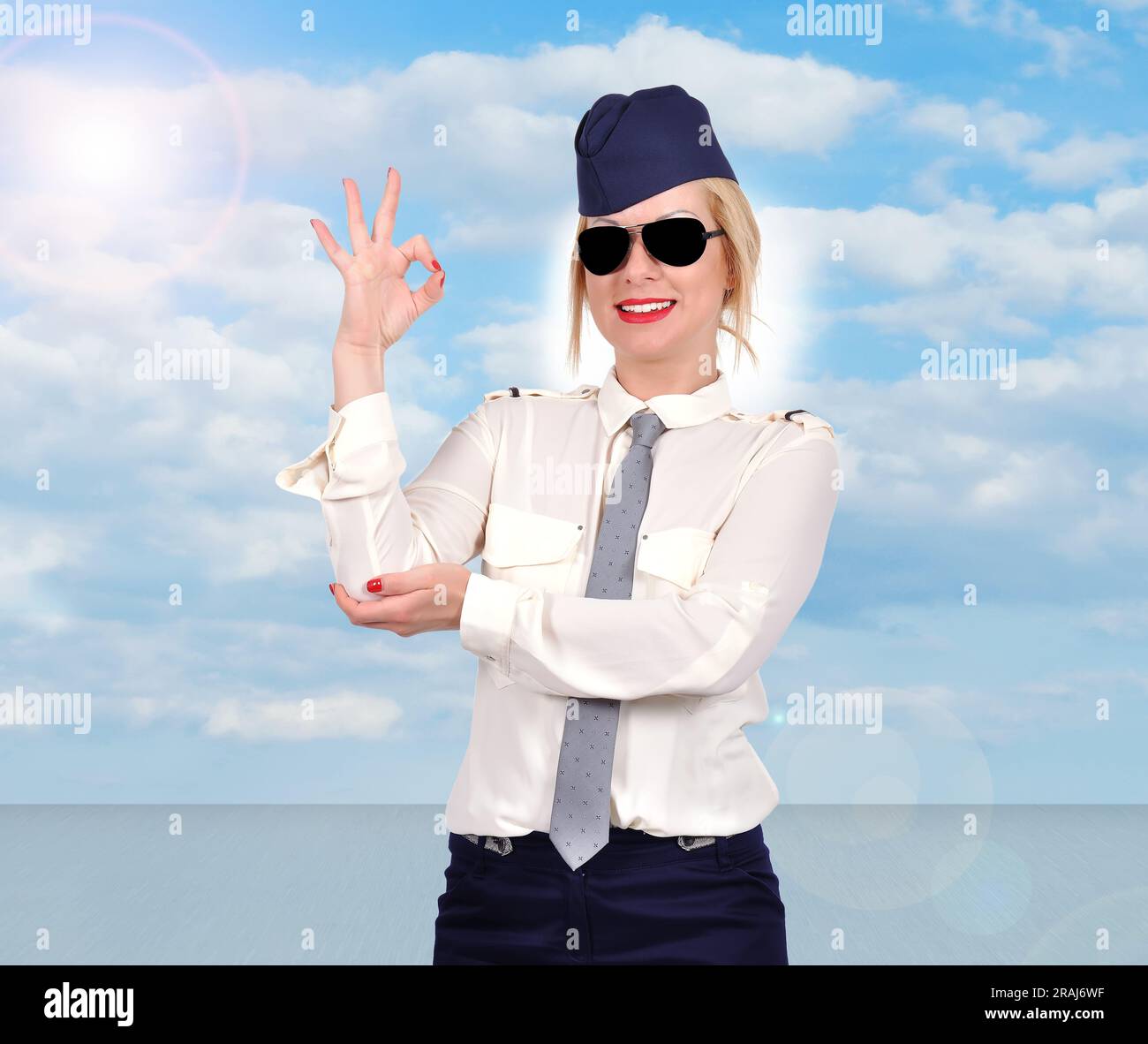 Flight attendant showing OK symbol on sky background Stock Photo - Alamy