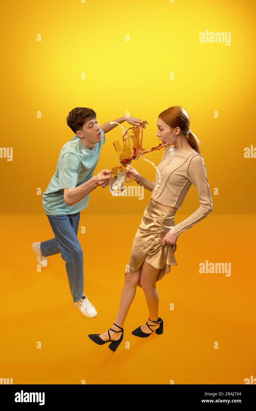 Creative image. Young man spilling beer and falling on woman spilling ...