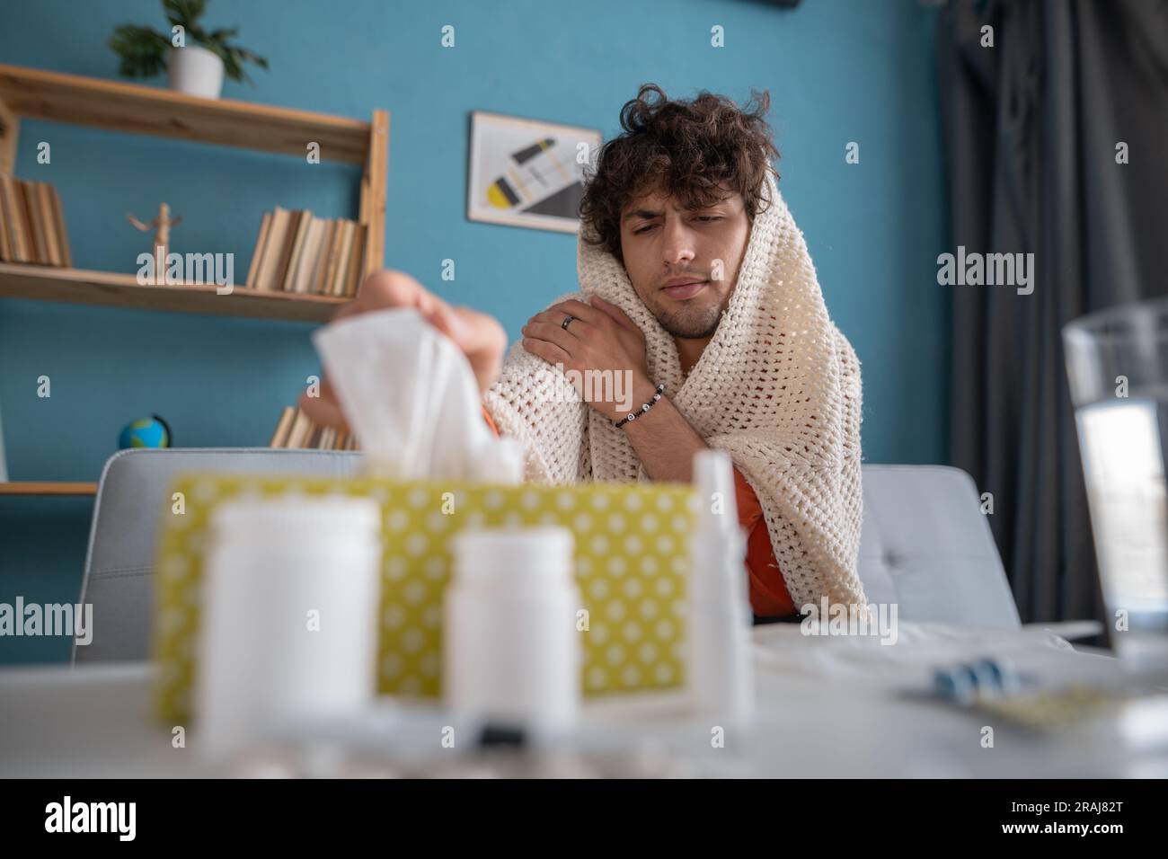 Arab sick sad man sits on couch at home suffers from runny nose flu ...