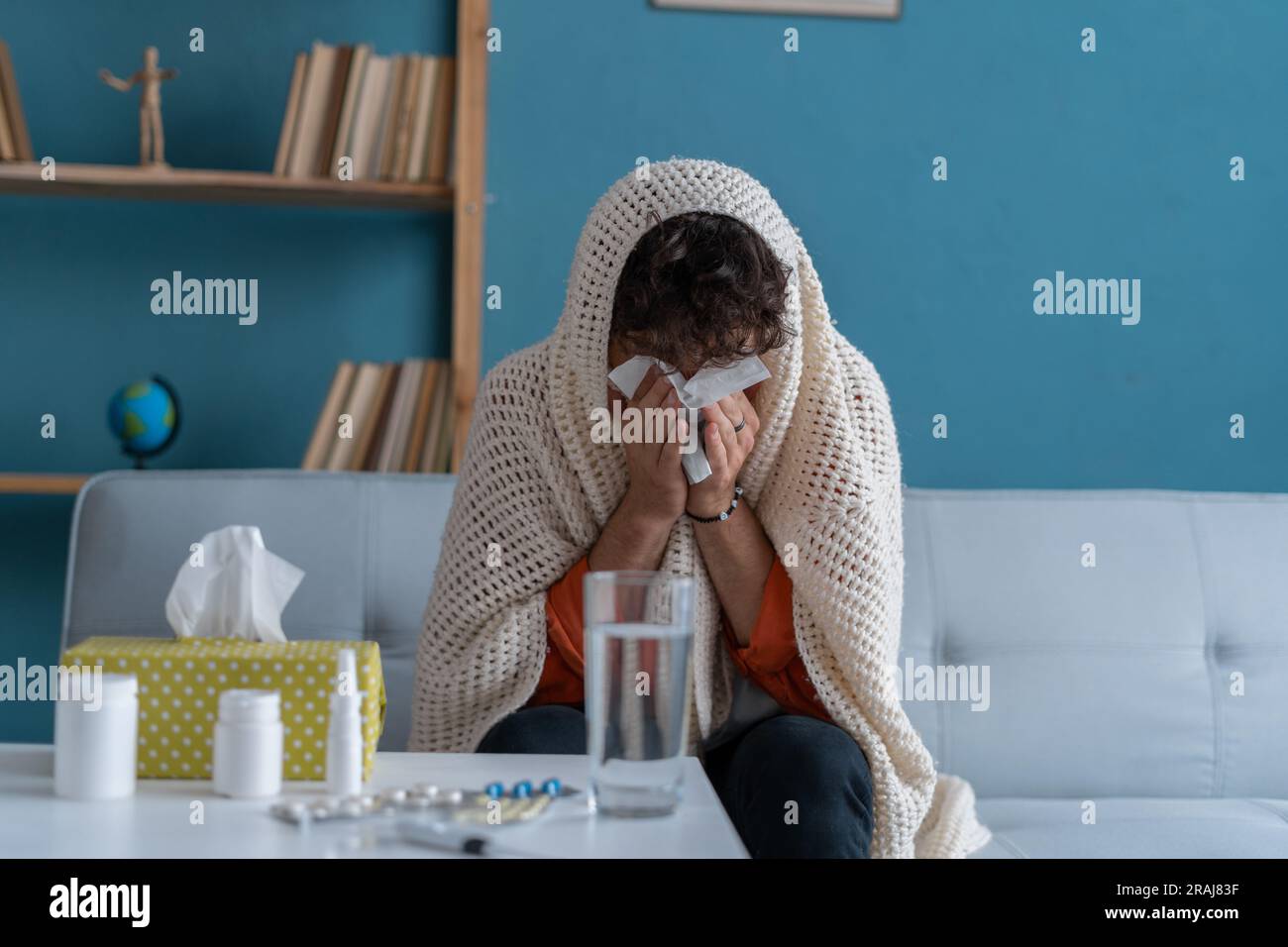 Sick young arab man sitting on sofa and sneeze with tissue paper at ...