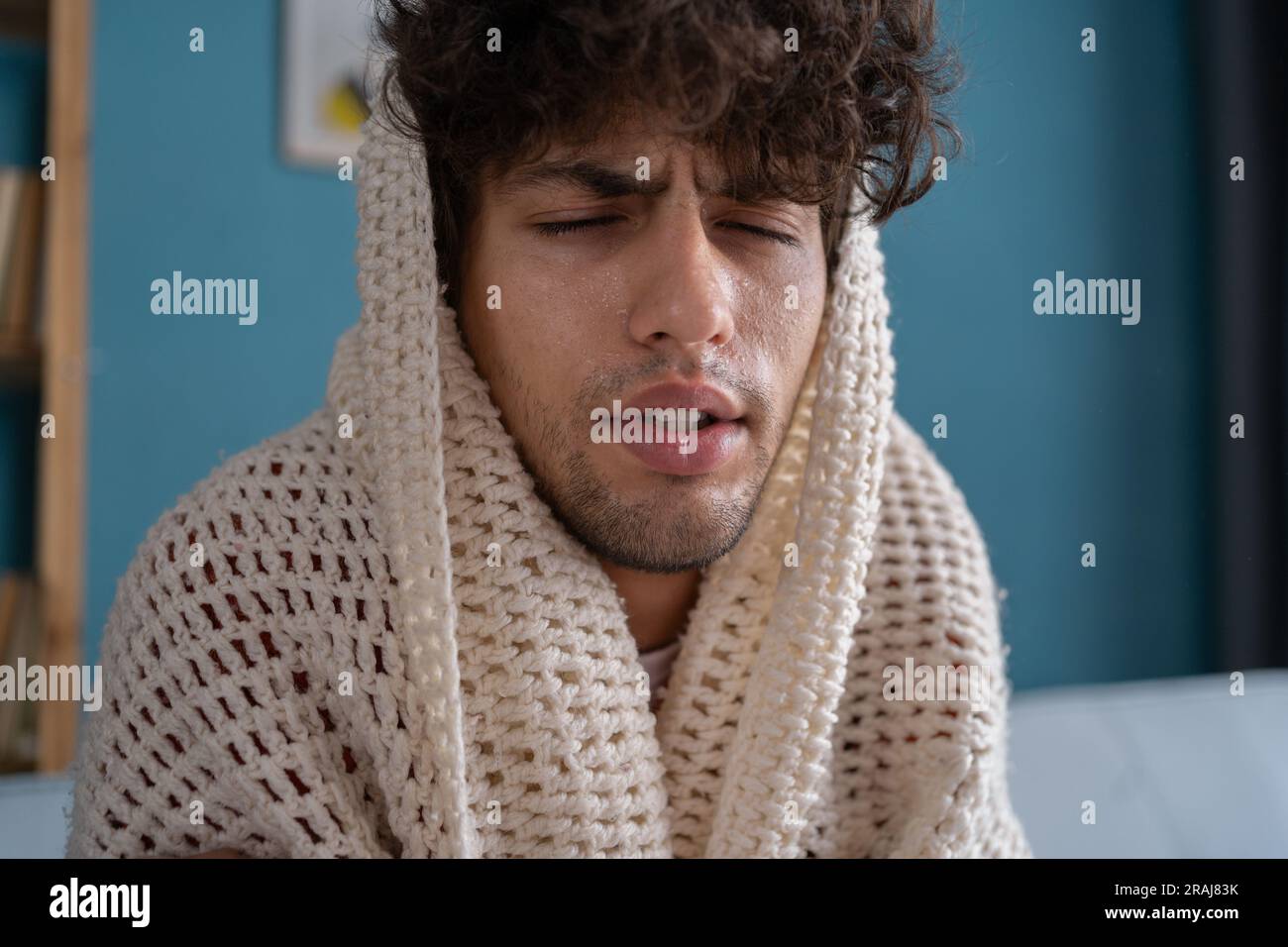 Sick young Arab man covered in a plaid suffers from a cold and high ...