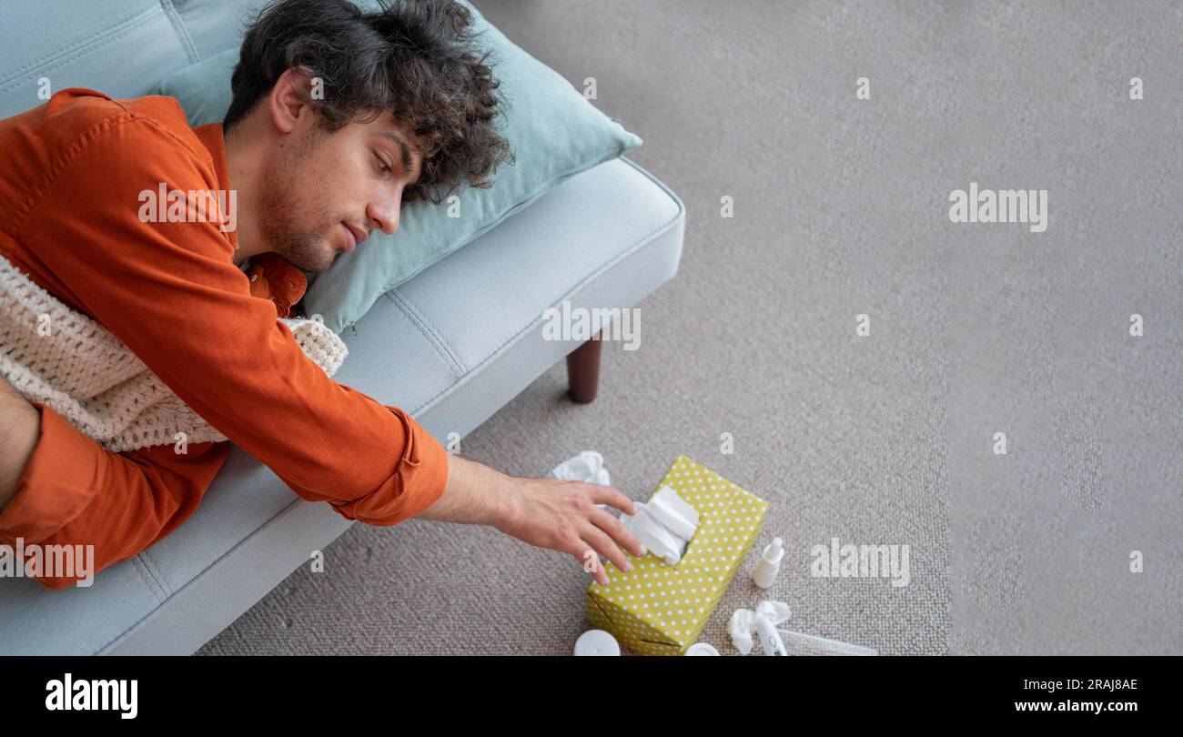 Sick man with fever lying on couch at home suffers from runny nose flu ...