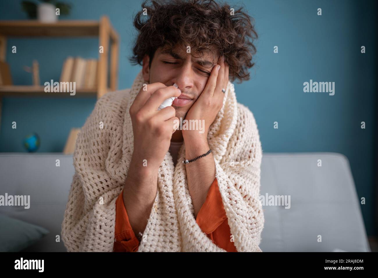 Young arabic man using nasal spray to help with cold. Sick with a ...