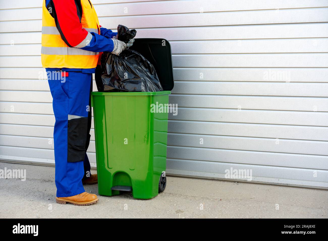 Janitor takes garbage out of trash container outdoors Stock Photo - Alamy