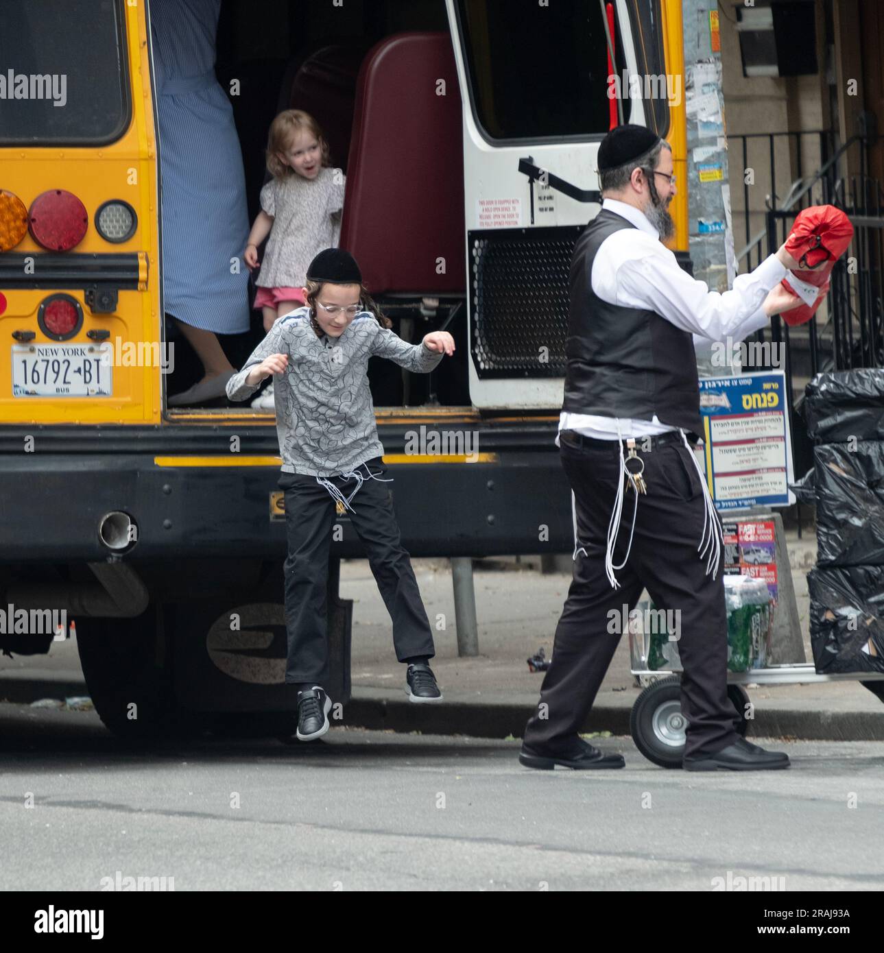 A young Hasidic boy jumps off his school bus to help his father with ...