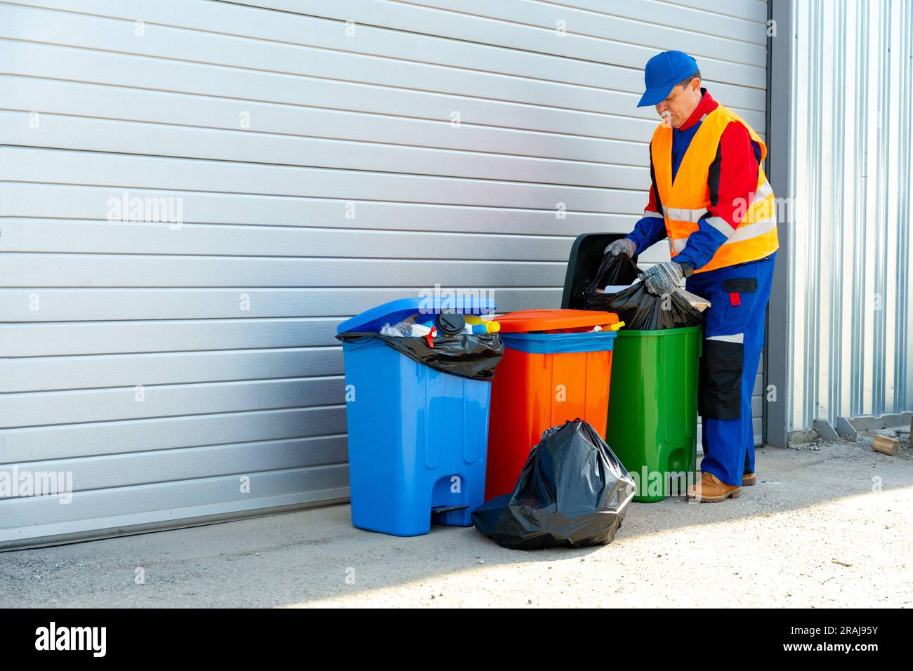 Janitor takes garbage out of trash container outdoors Stock Photo - Alamy