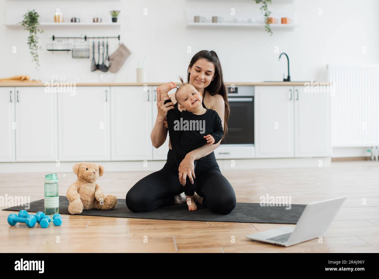 Adorable little child doing splits with mother's support while ...