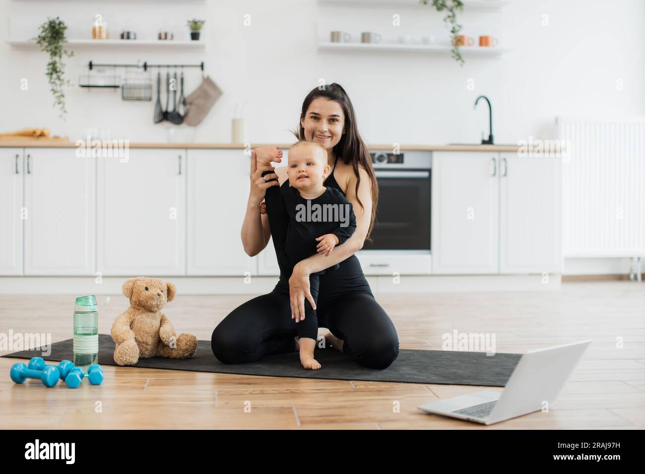 Adorable little child doing splits with mother's support while ...