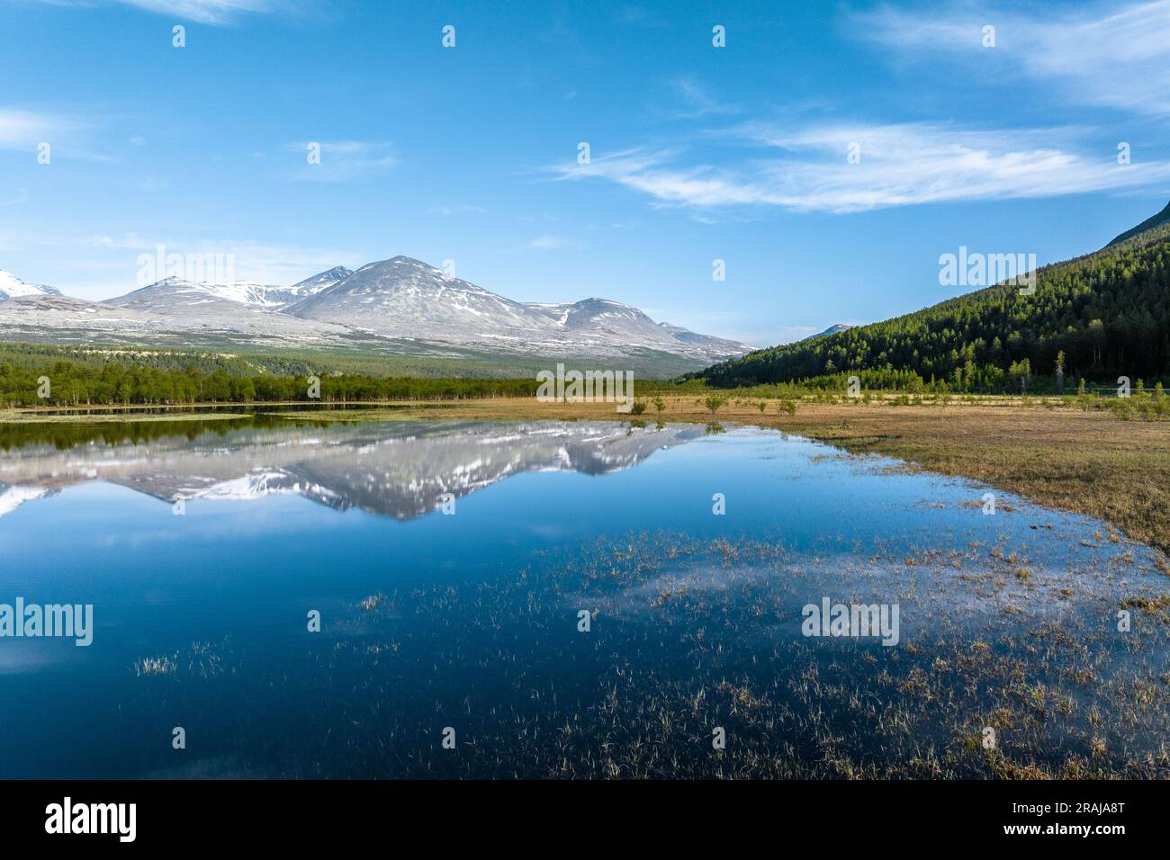 Reflection of mountains on a calm lake in Rondane National Park, Norway ...