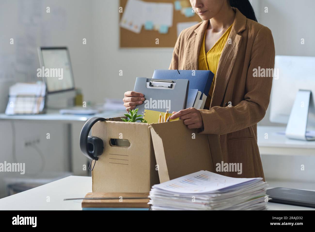 Young businesswoman packing her things in box during move in new office ...