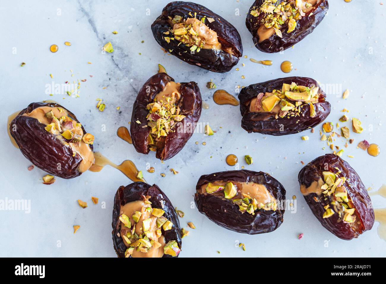 Dates stuffed with peanut butter and pistachios on a white marble ...