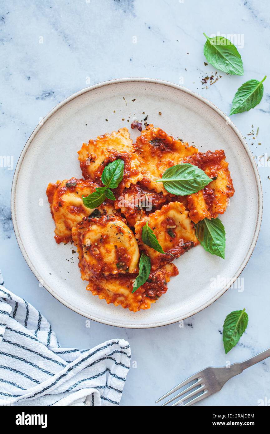 Ravioli with ricotta, tomato sauce and basil, white marble background ...