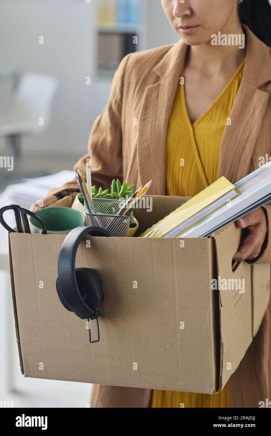 Vertical image of businesswoman packing things in box after job loss ...