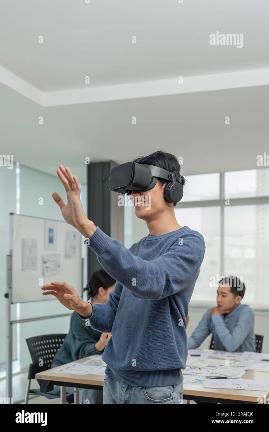 A cheerful and excited young Asian male developer tested a new VR game ...