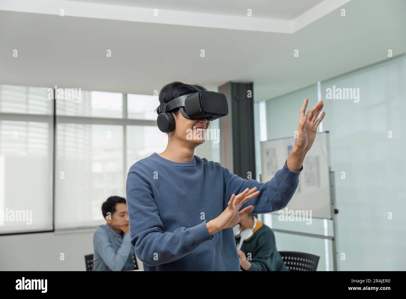 A cheerful and excited young Asian male developer tested a new VR game ...