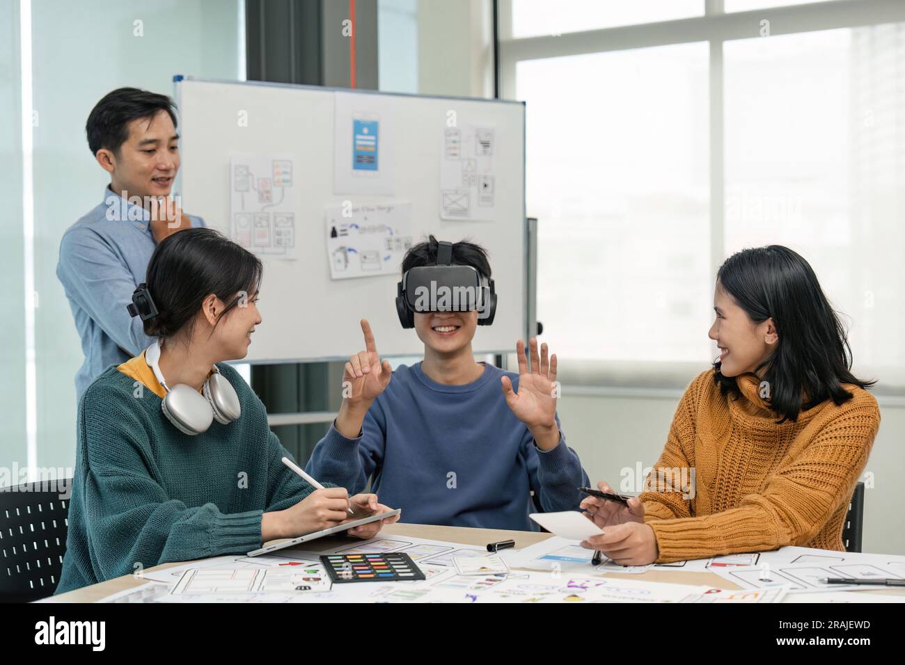 Diverse development team testing virtual reality headset, brainstorming ...