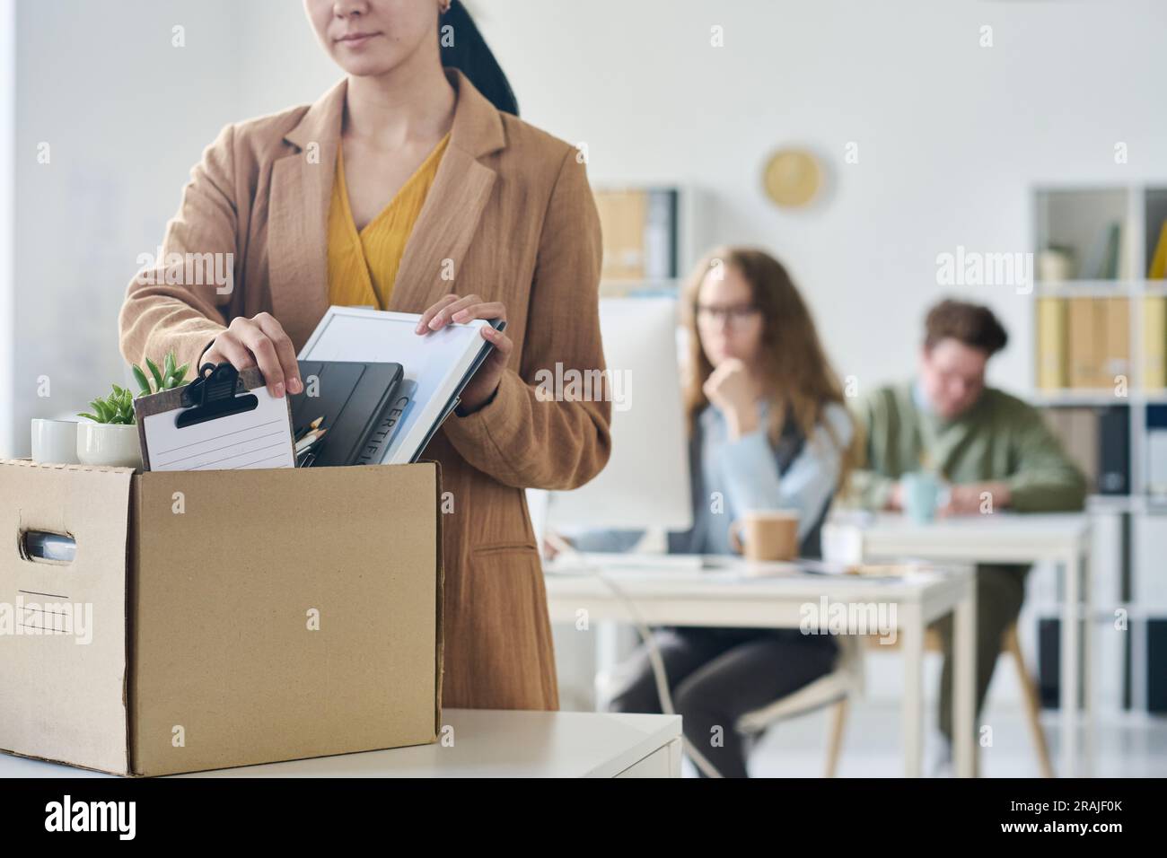 Young businesswoman packing her things in cardboard box in office after ...