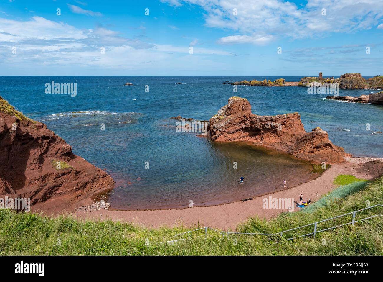 People swimming in sea at beach cove on sunny day, Dunbar, East Lothian ...