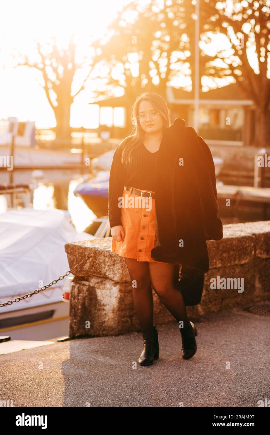 Outdoor portrait of asian plus size model, holding black faux fur coat ...