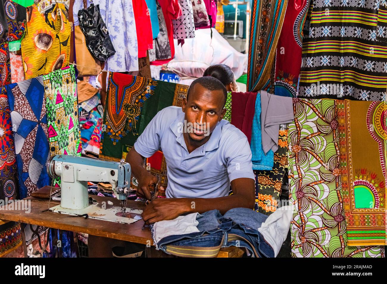 A man with an old sewing machine and fabric in the market of Praia ...