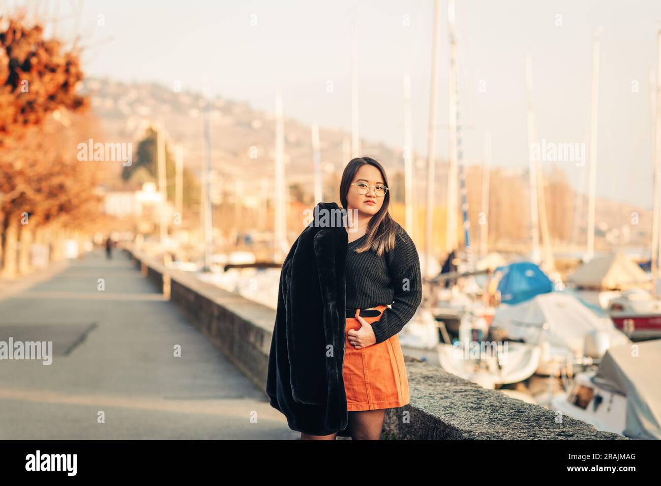 Outdoor portrait of asian plus size model, holding black faux fur coat ...