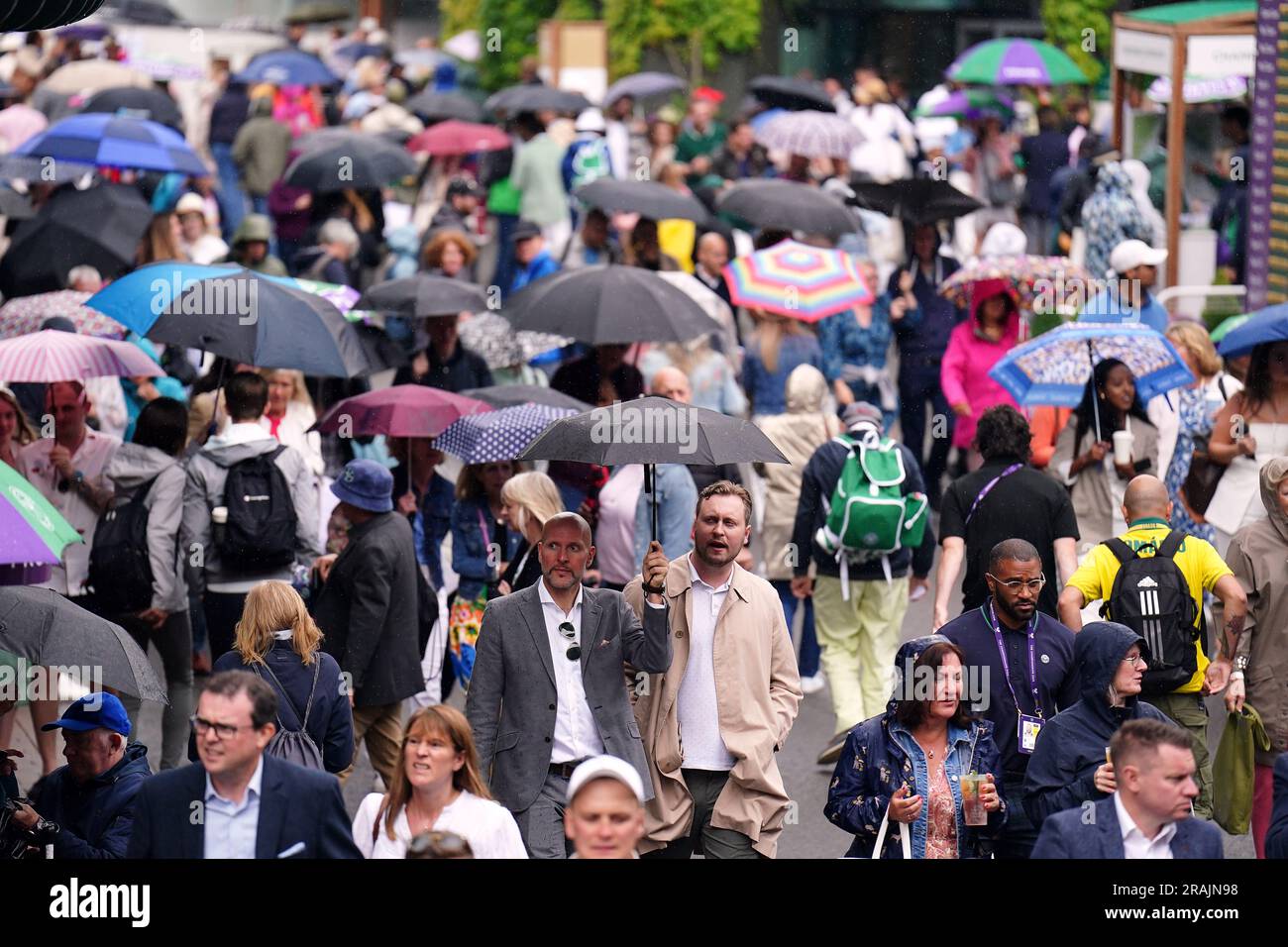 Spectators shelter from the rain as they make their way around the ...