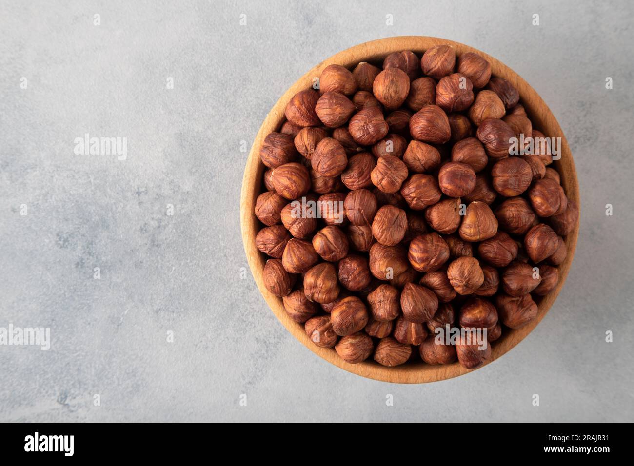 Top view of a bowl full of peeled hazelnuts on light blue background ...