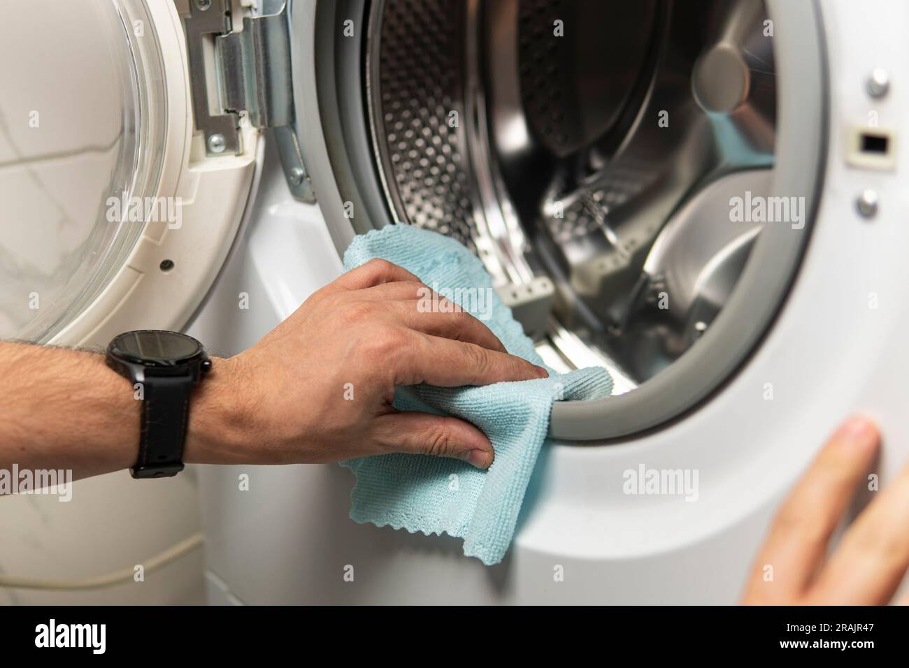 A man cleaning a dirty, moldy rubber seal on a washing machine. Mold ...