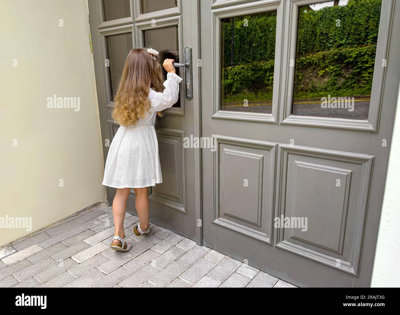Child peeking through the door window Stock Photo - Alamy