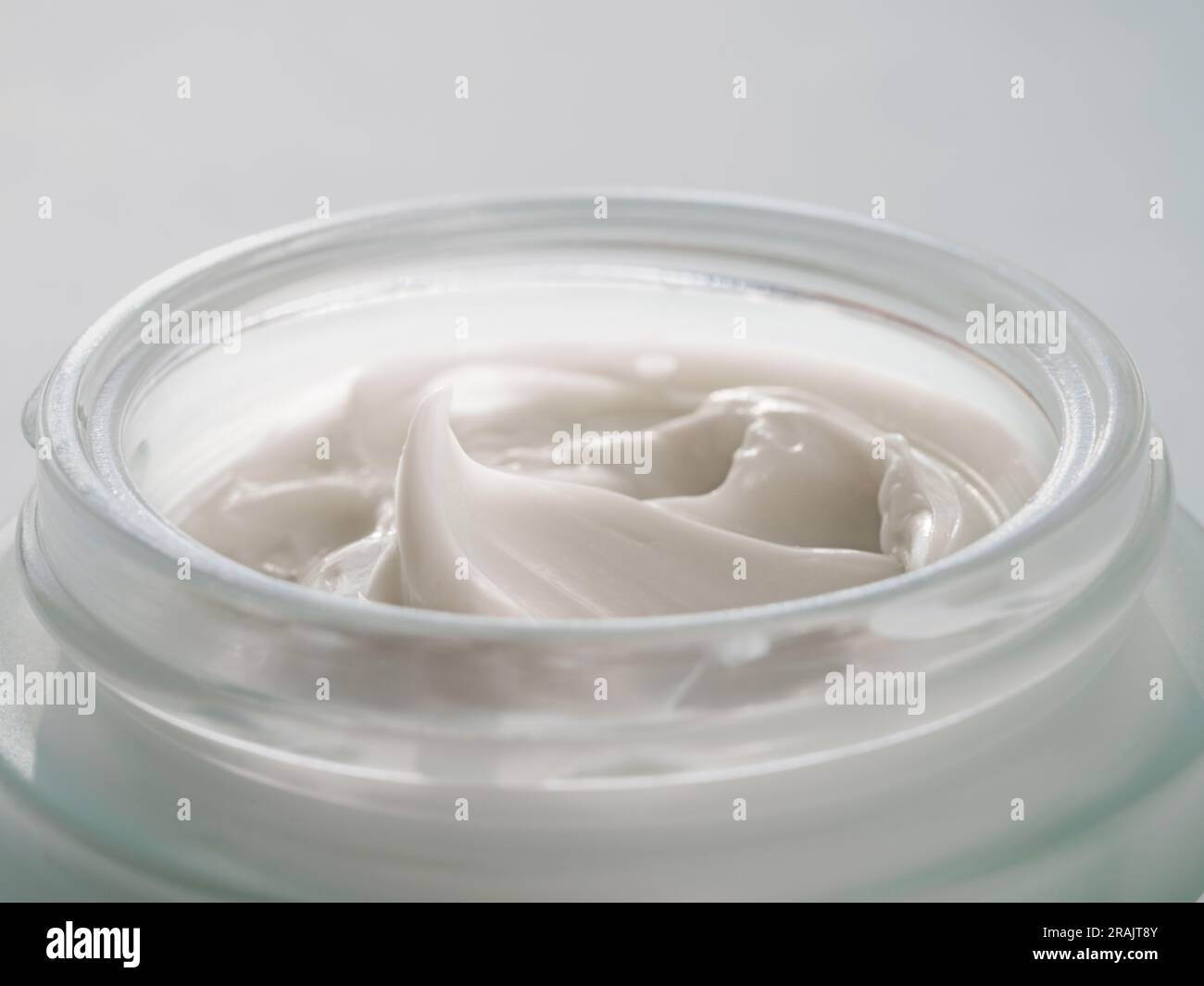 Glass jar of luxury face cream. Close up open jar with beautiful swirls ...