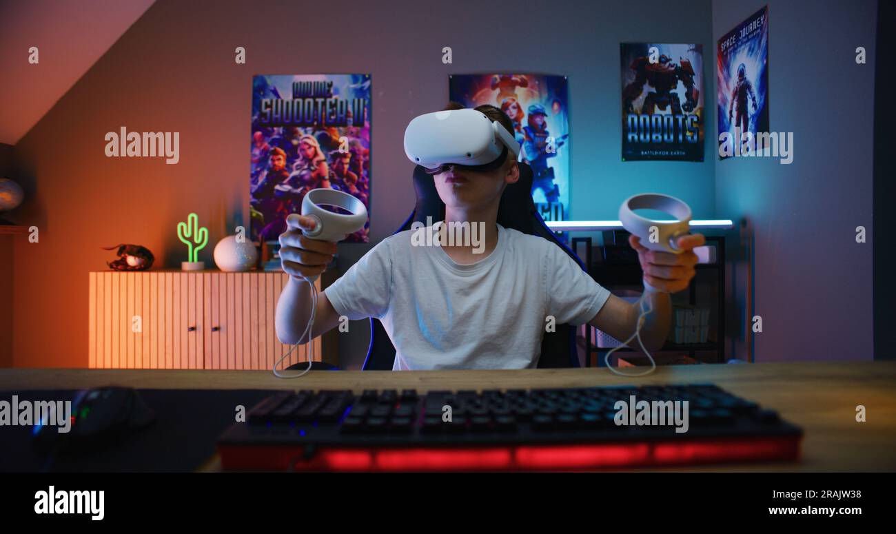Young gamer in VR headset plays virtual online video game using ...