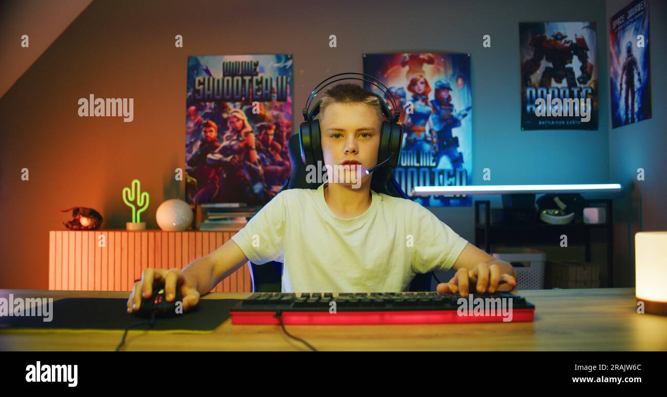 Young gamer in headphones speaks with teammates, plays online video ...
