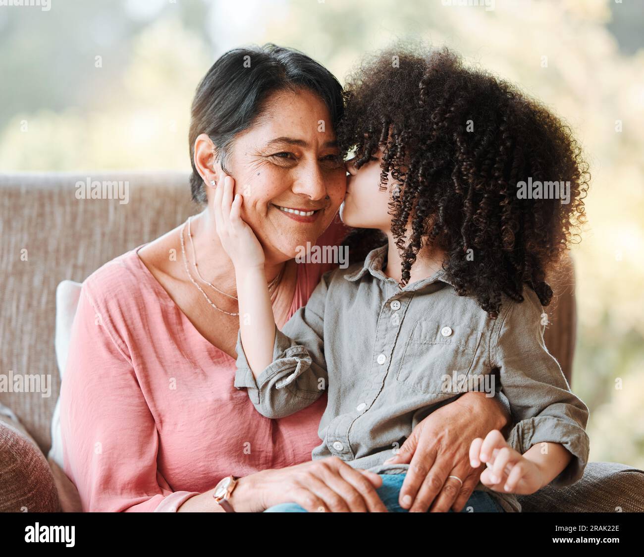 Kiss, family and grandmother with child on a sofa happy, sweet and bond ...