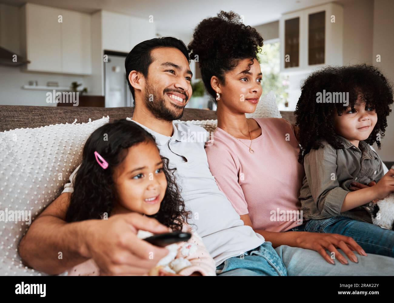 Mother, father and children on couch, watching tv and happy family ...