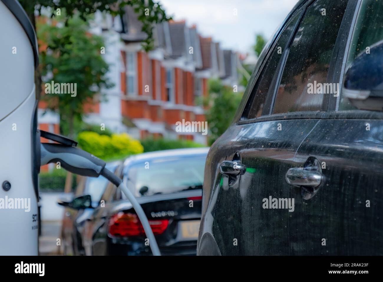 Electric car plugged in and changing on urban city street Stock Photo ...