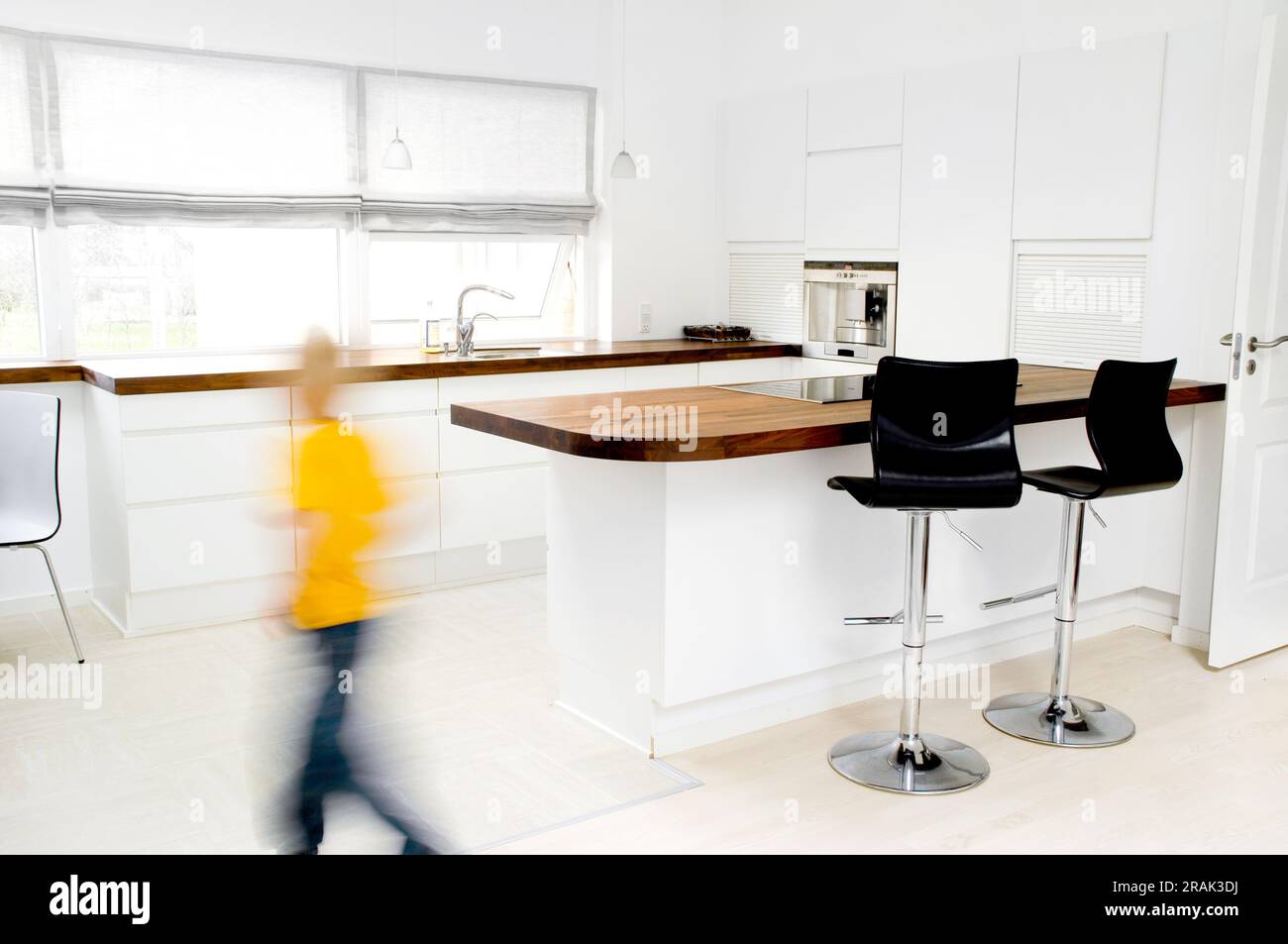 A modern white kitchen. Note the boy in the picture is in motion blur ...