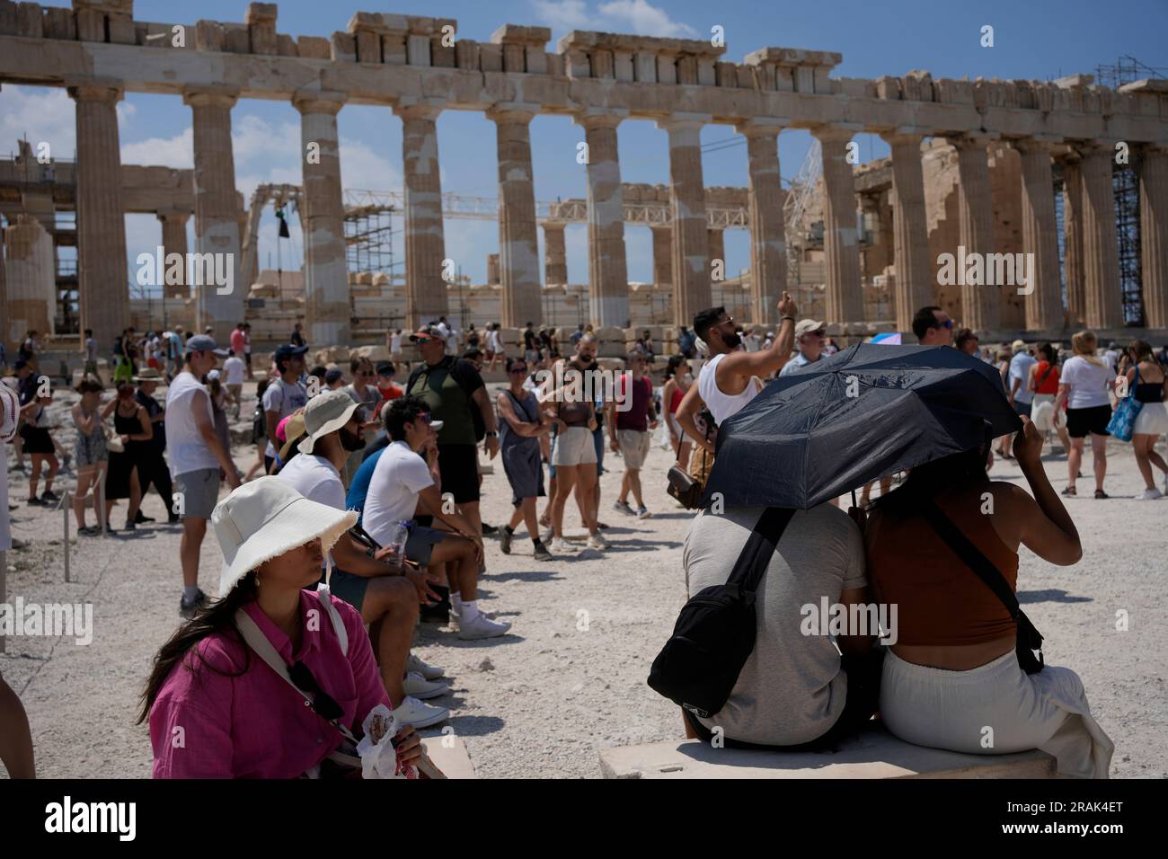 Tourists visit the Parthenon temple, background, atop of the Acropolis ...
