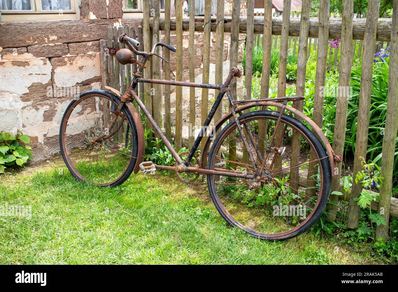 Old rusty damaged bicycle leaning at a wooden fence in a rural area ...