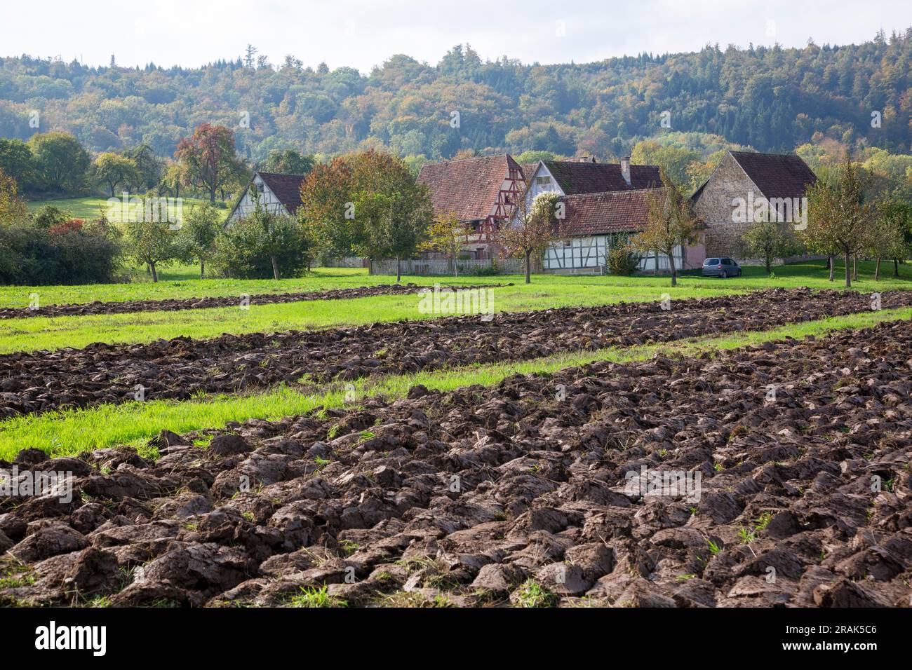 Agriculture scenery with partly ploughed field in front of farm house ...